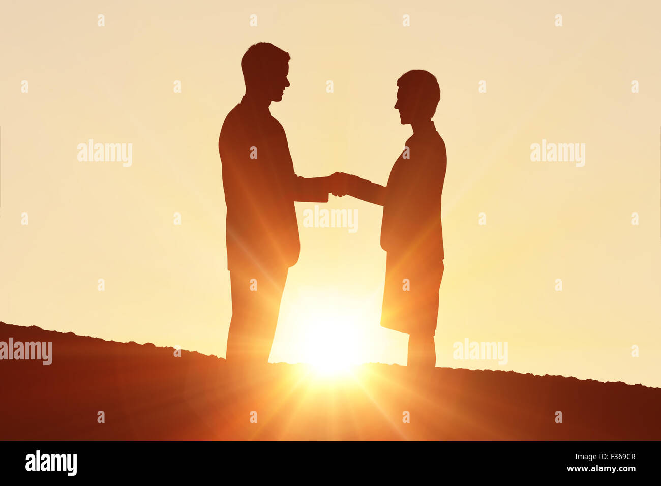 Composite image of silhouettes shaking hands Stock Photo - Alamy