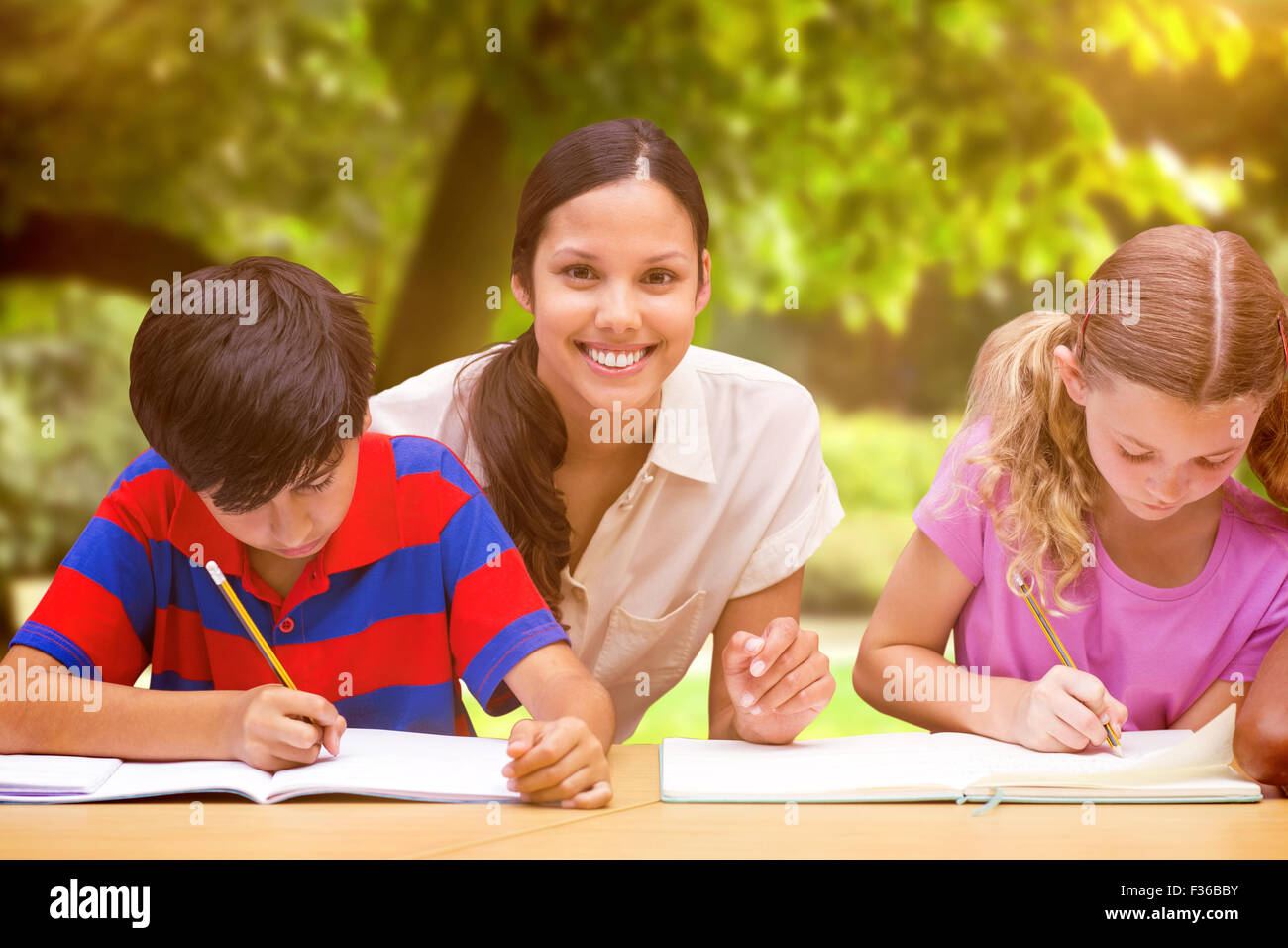 Composite image of pretty teacher helping pupils in library Stock Photo ...