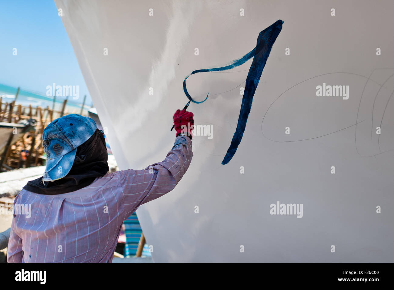 An Ecuadorian shipbuilder paints the ship's name on the stem of a ...