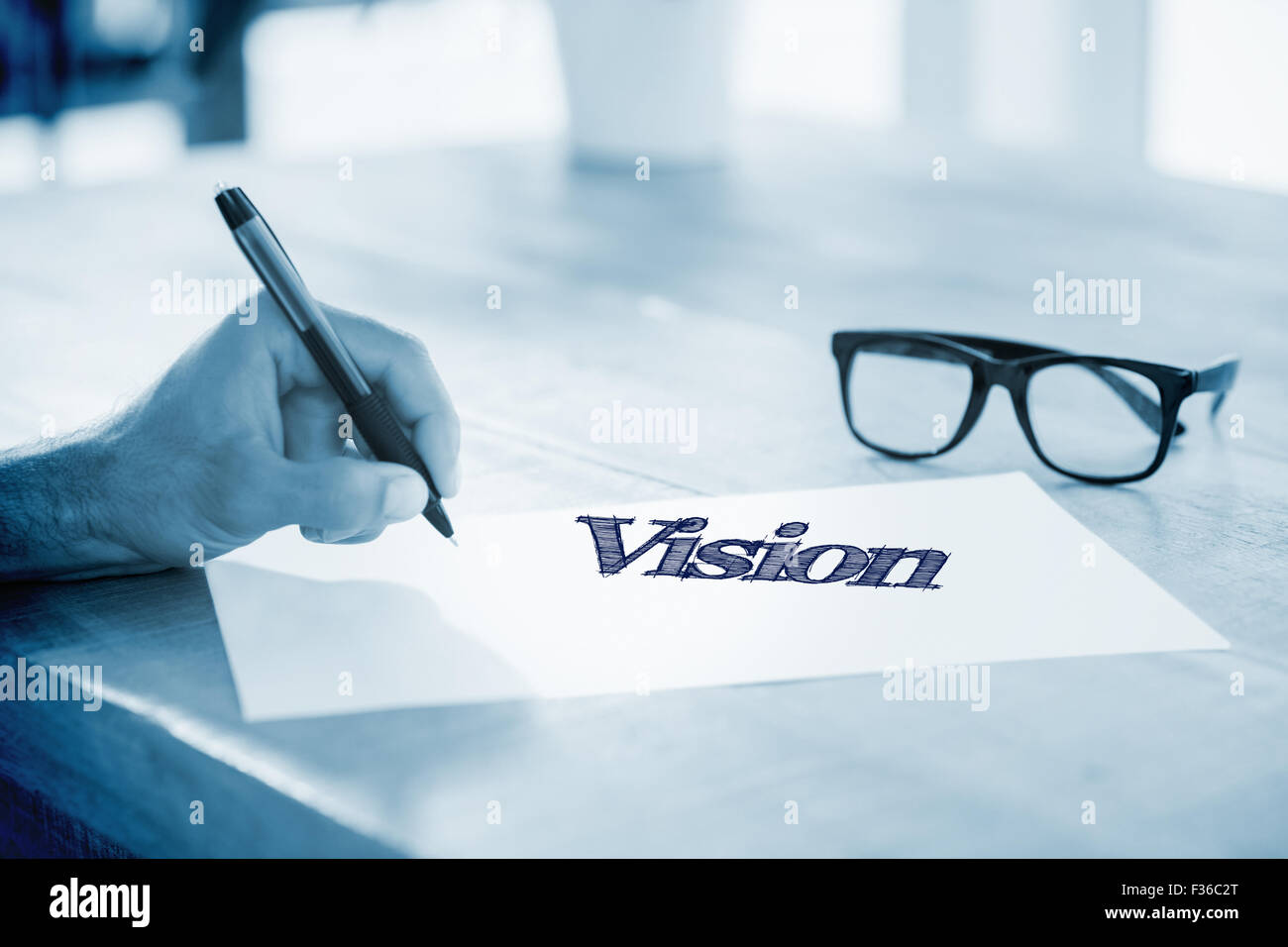 Vision against side view of hand writing on white page on working desk ...