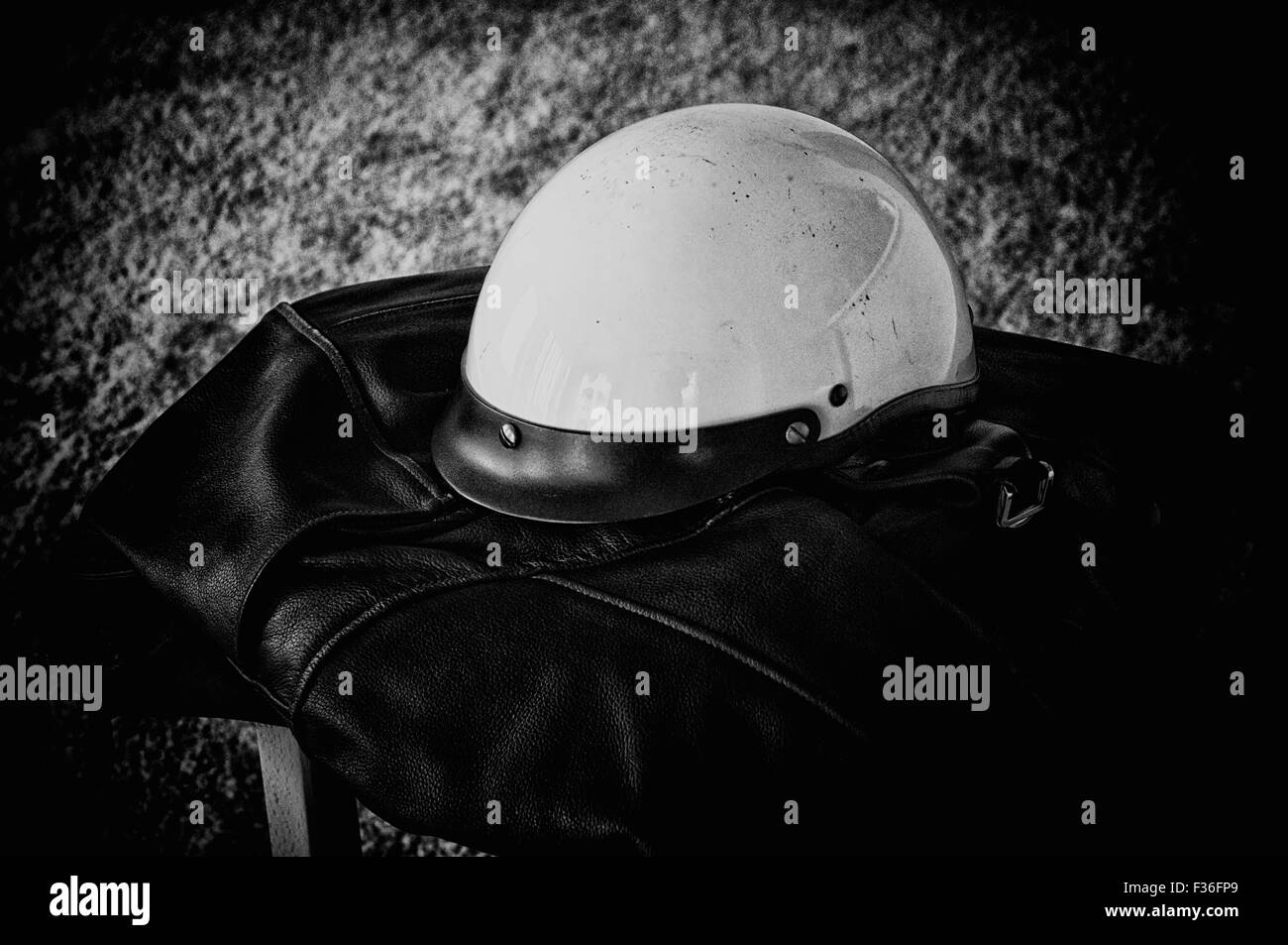 A grainy gritty image of a battered white motorcycle helmet resting on ...