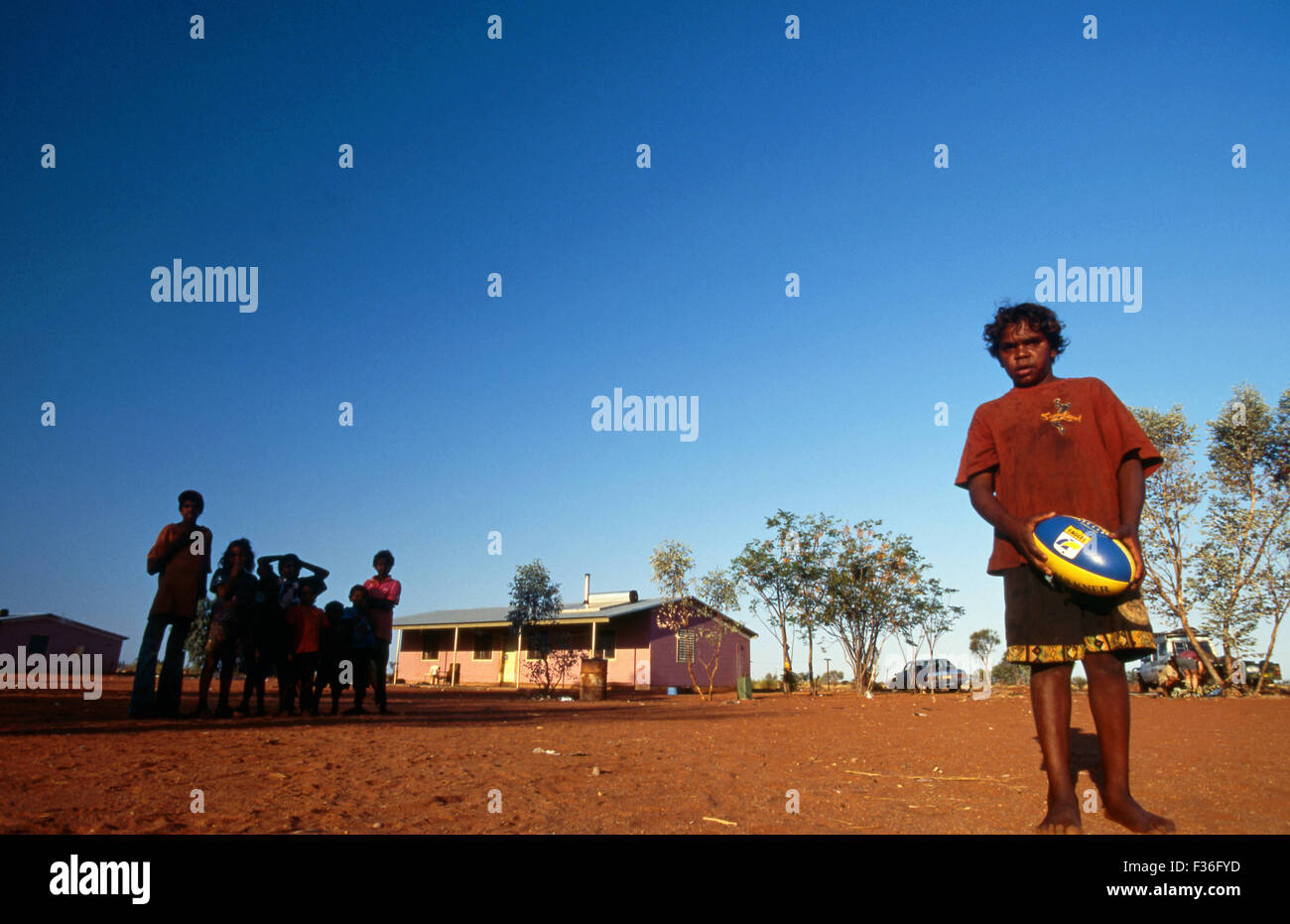 Young Aboriginal boy playing football, Yuelamu (Mount Allan) in the ...