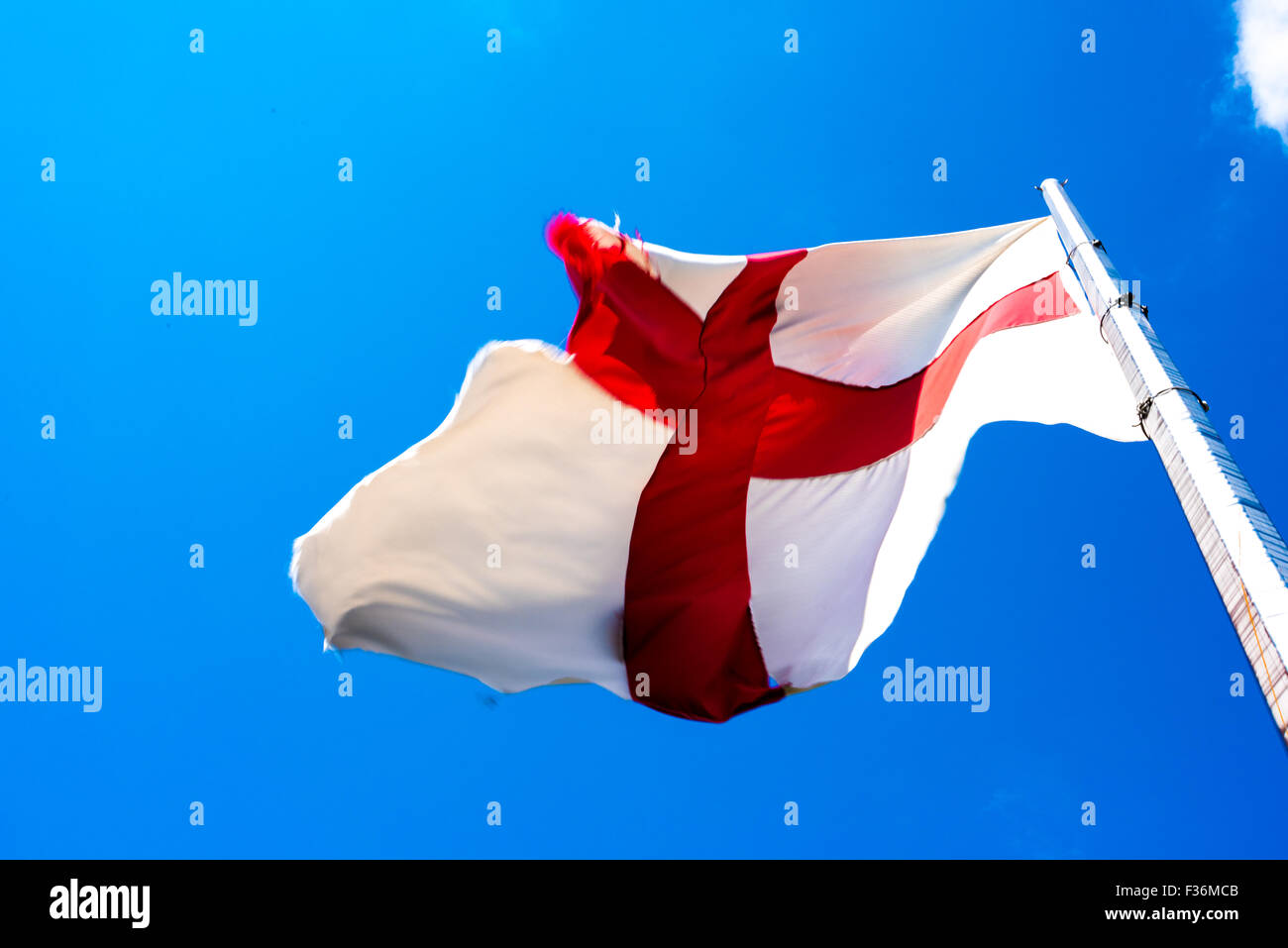 A Torn England flag blowing in the wind against a blue sky in ...