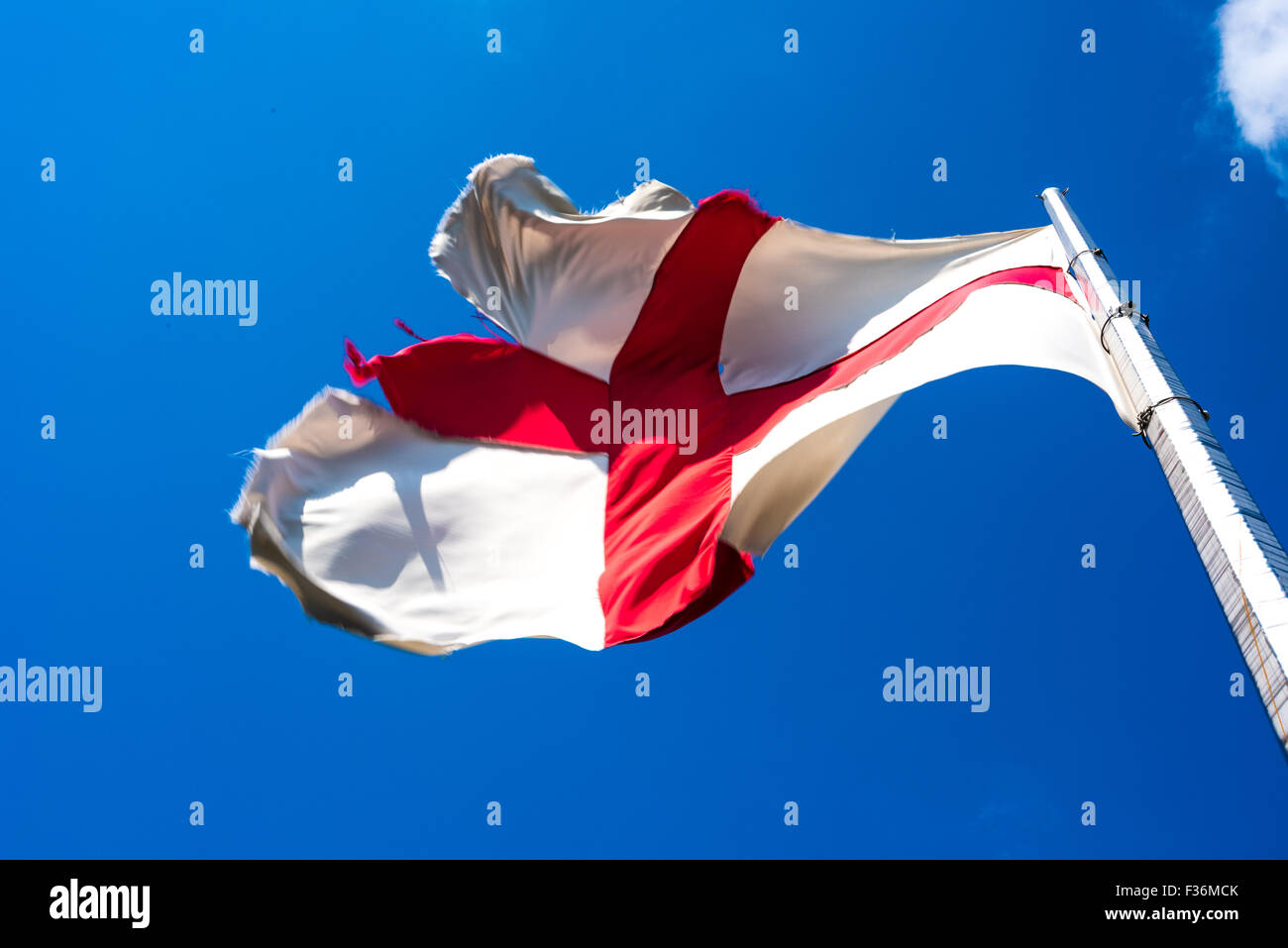 A Torn England flag blowing in the wind against a blue sky in ...