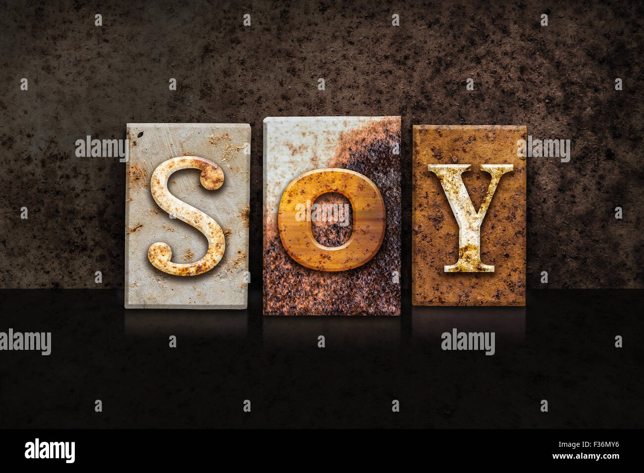 The word "SOY" written in rusty metal letterpress type on a dark ...