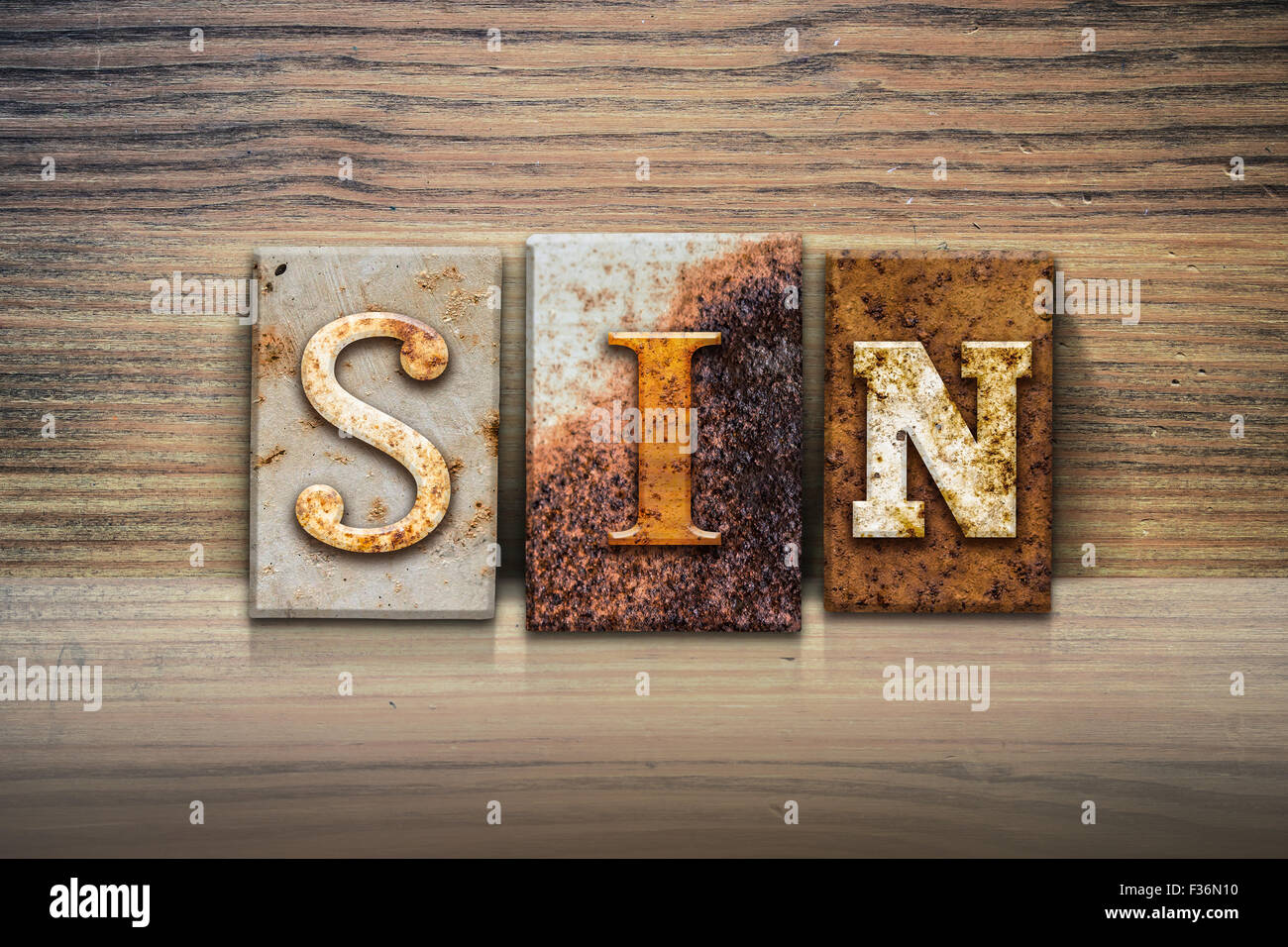 The word "SIN" written in rusty metal letterpress type sitting on a ...