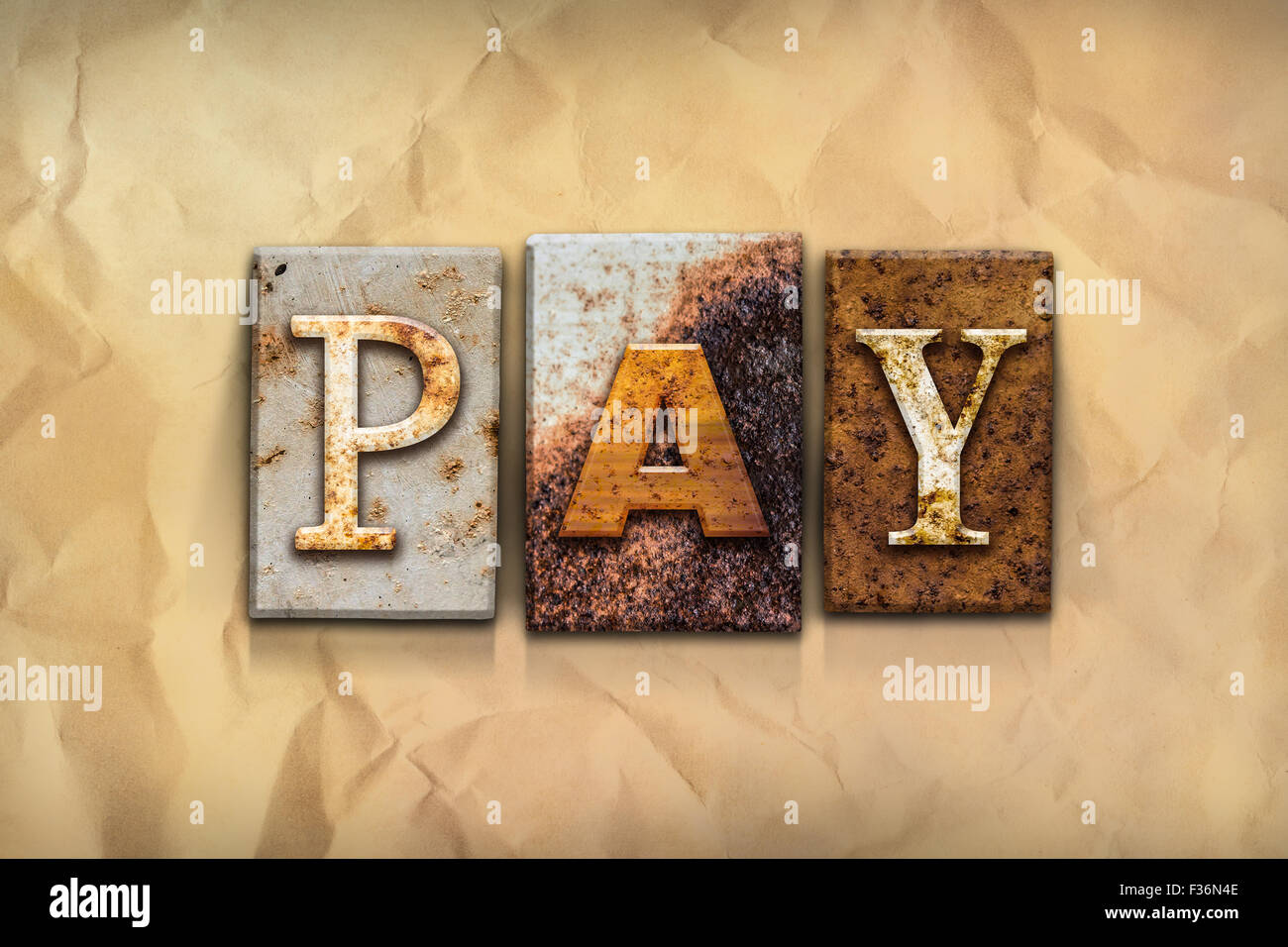 The word "PAY" written in rusty metal letterpress type on a crumbled ...