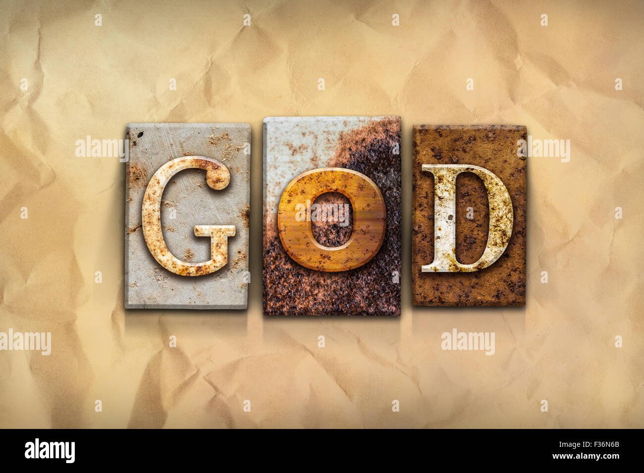 The word "GOD" written in rusty metal letterpress type on a crumbled ...