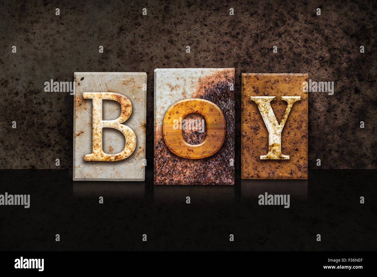 The word "BOY" written in rusty metal letterpress type on a dark ...