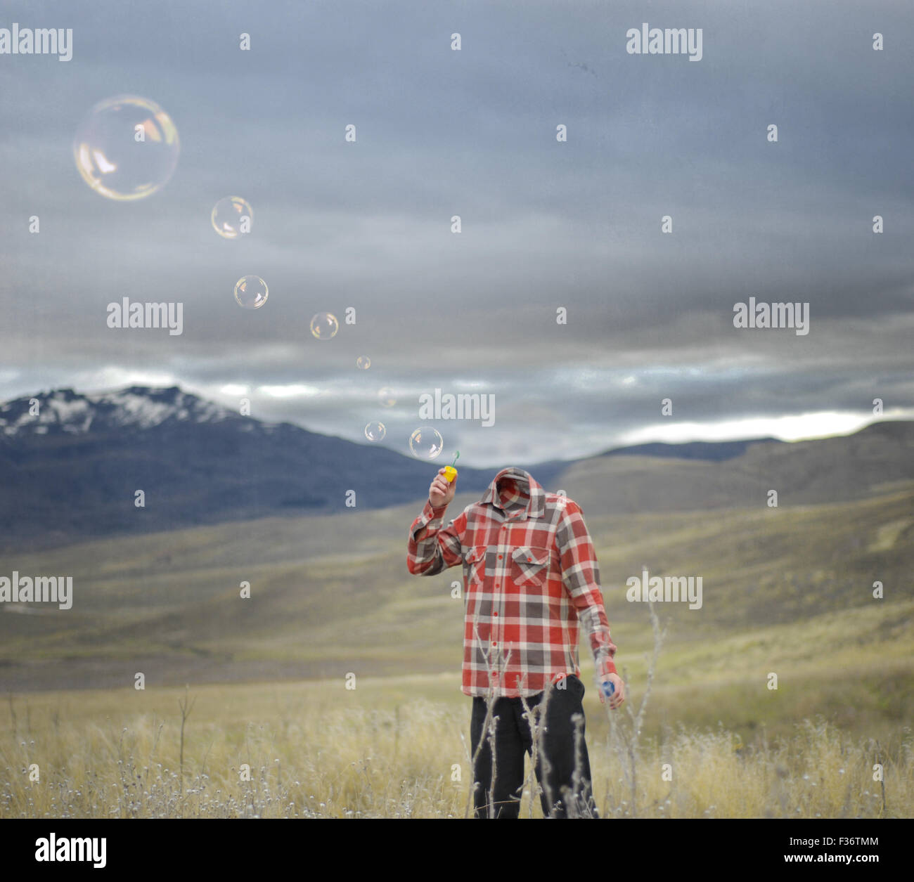 Headless Man blowing bubbles mountains stormy sky Stock Photo - Alamy