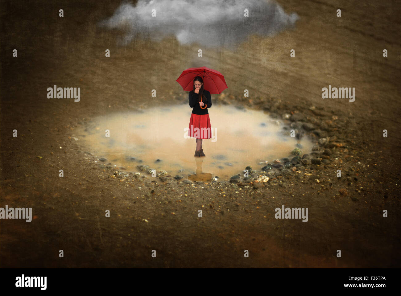 Miniature girl standing in a puddle with a red umbrella with a big ...