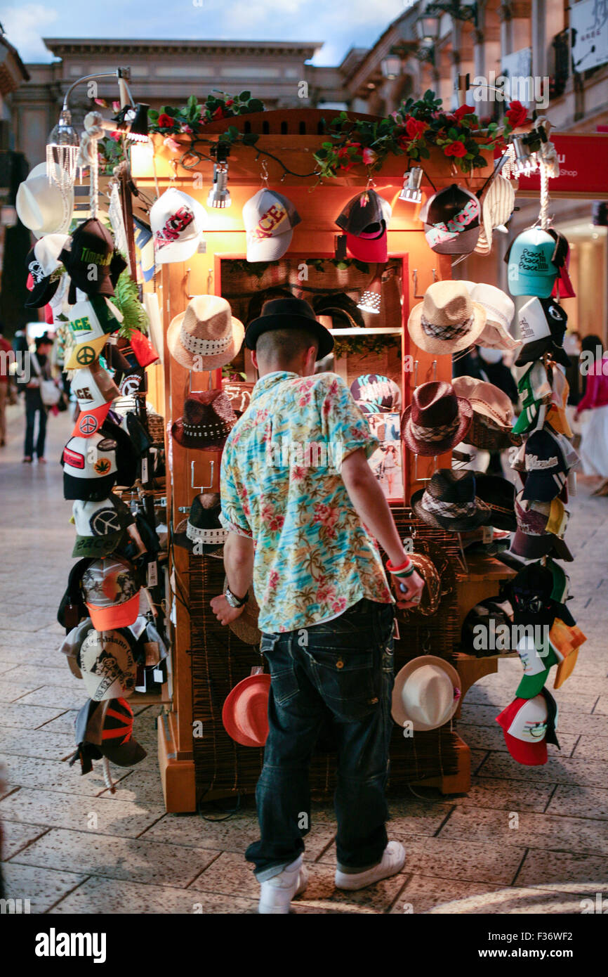 Hat kiosk in shopping center with worker wearing a floral pattern shirt ...