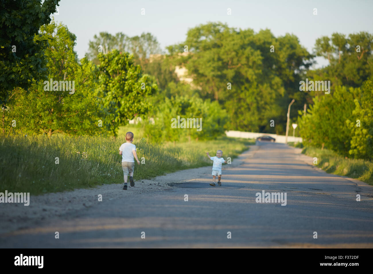 Two boys run on the road Stock Photo - Alamy