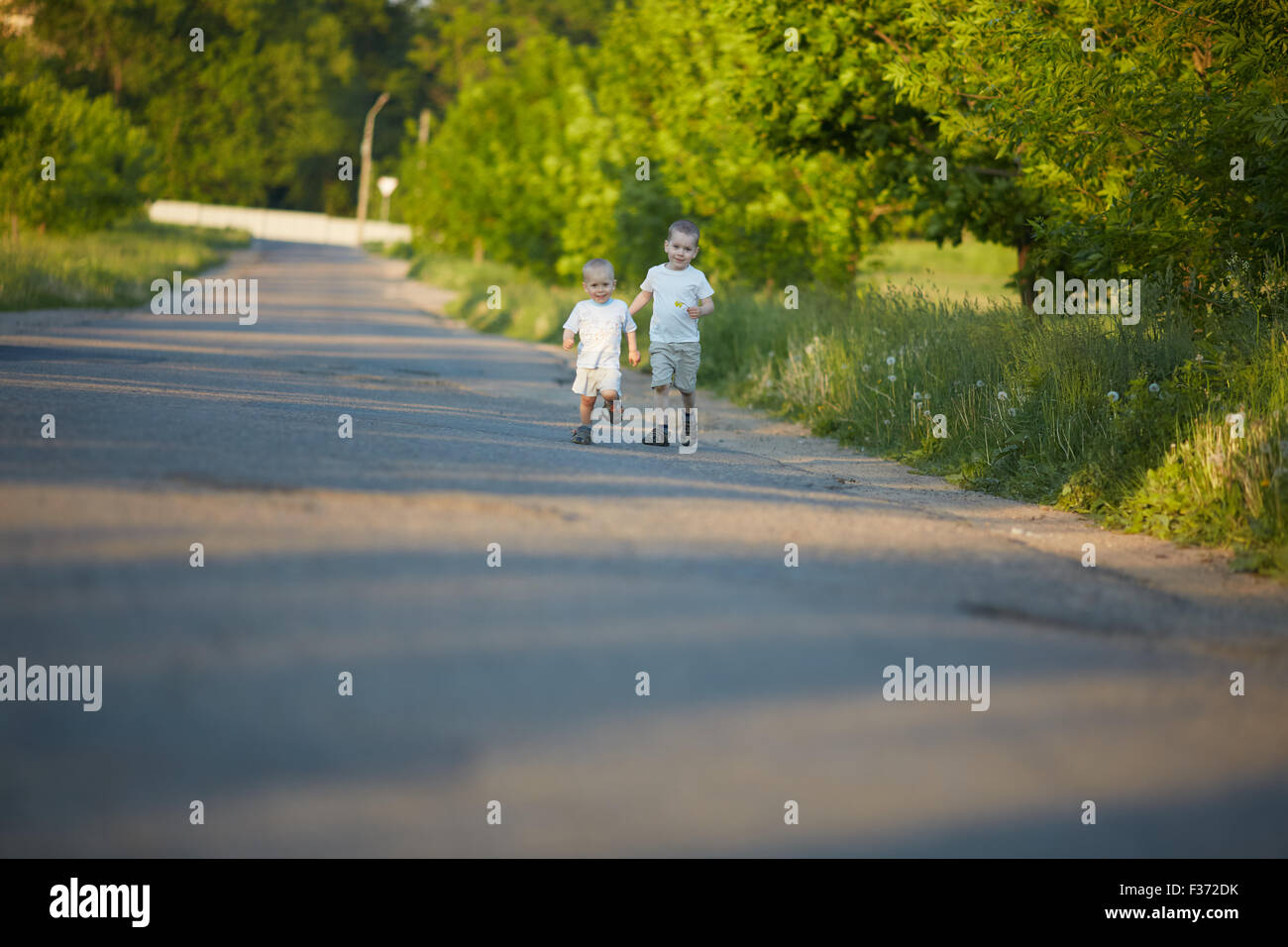 Two boys run on the road Stock Photo - Alamy