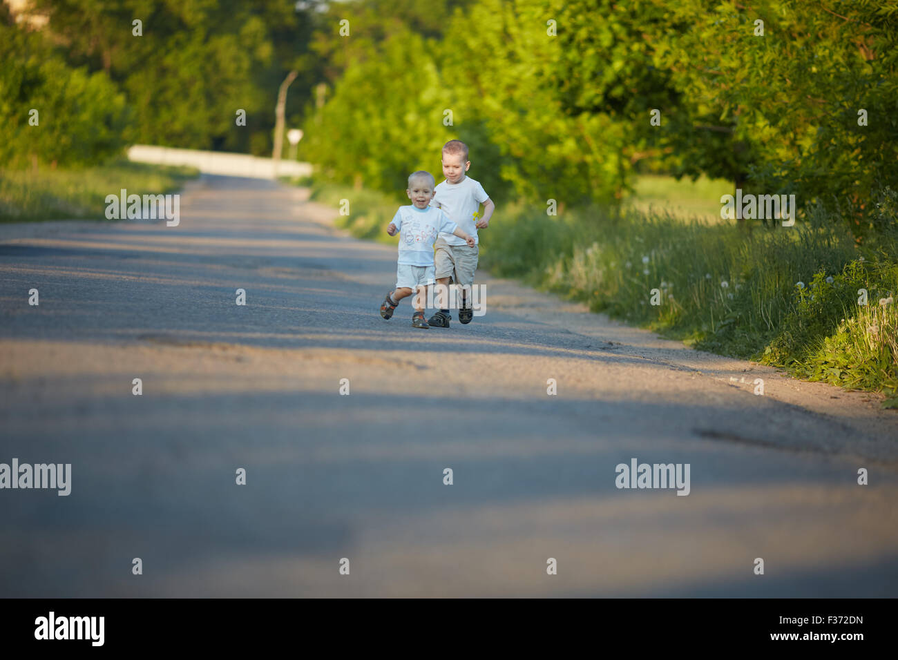 Two boys run on the road Stock Photo - Alamy