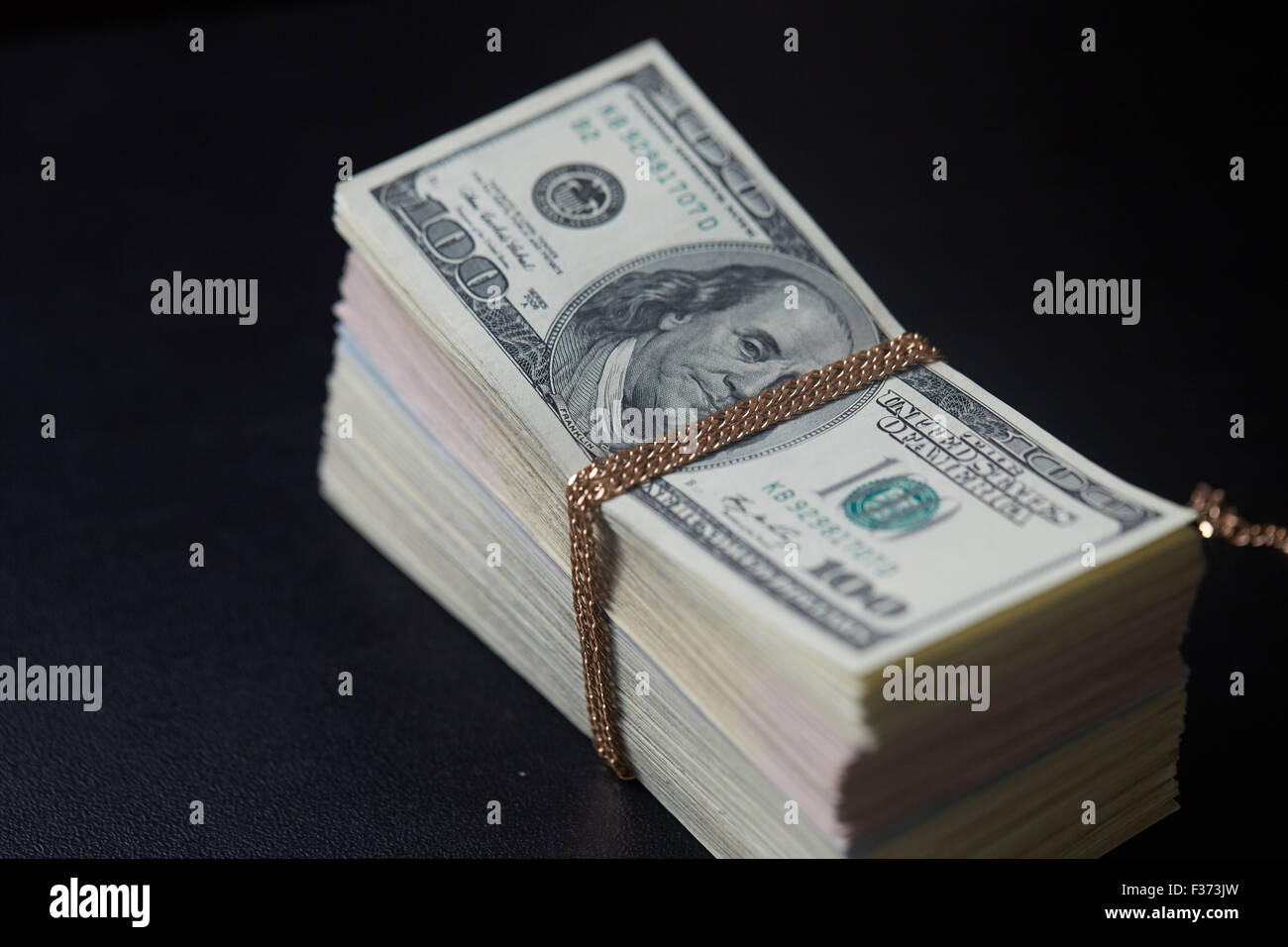 a bundle of money tied with gold chain Stock Photo - Alamy