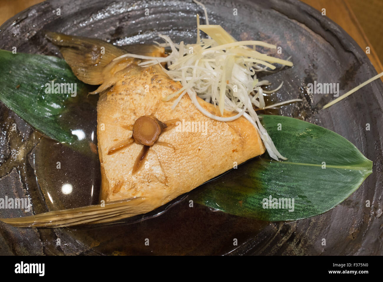 Hamachi cooked in sauce on black ceramic plate Stock Photo - Alamy
