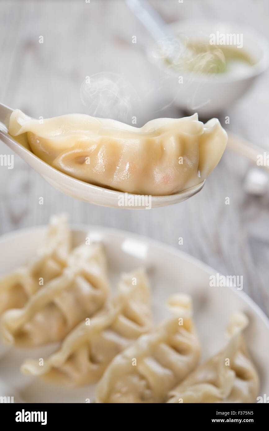 Fresh boiled dumpling on spoon with hot steams. Chinese food on old ...