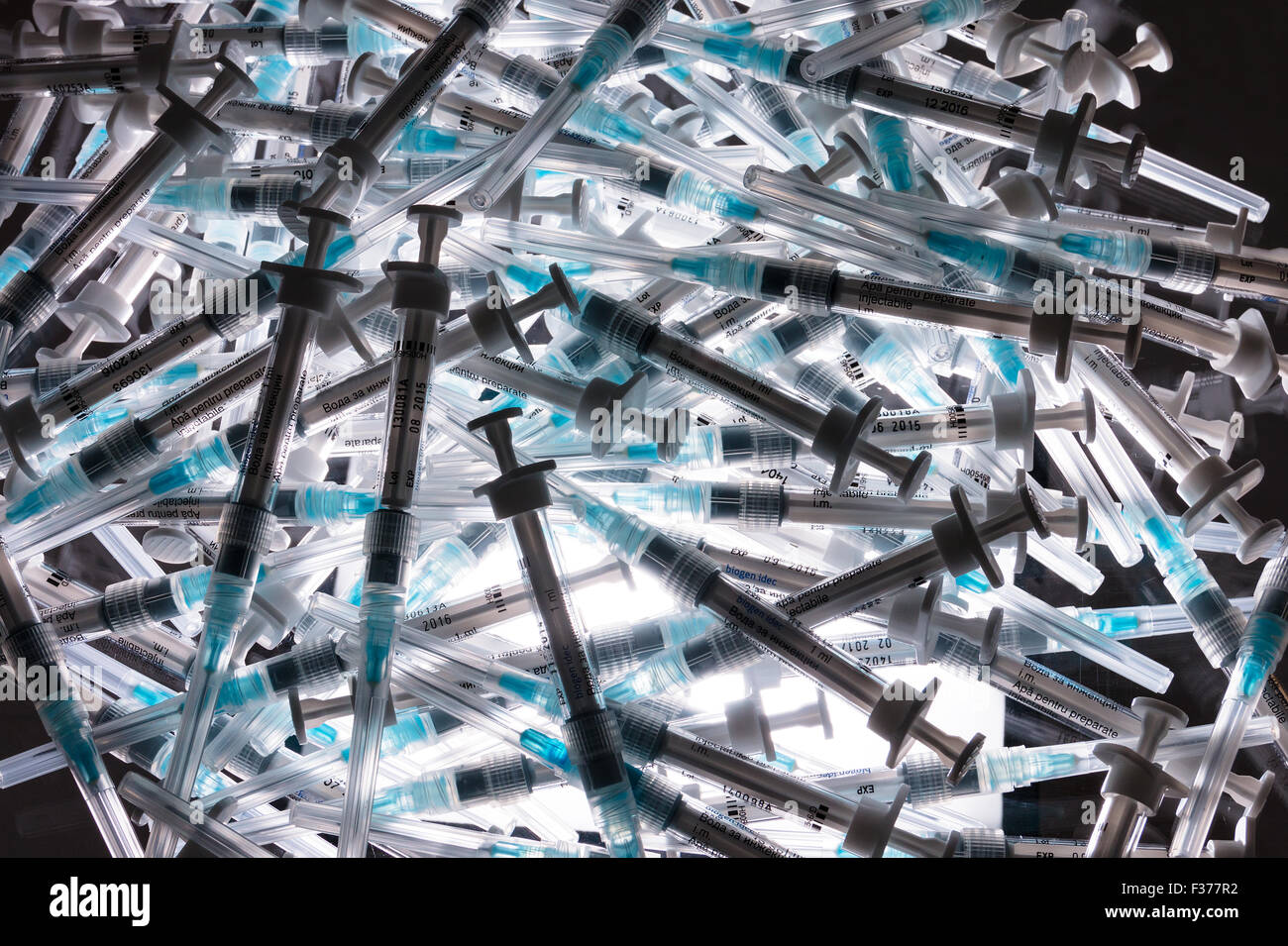 A bunch of used syringes, lit from below. The text on them does not ...