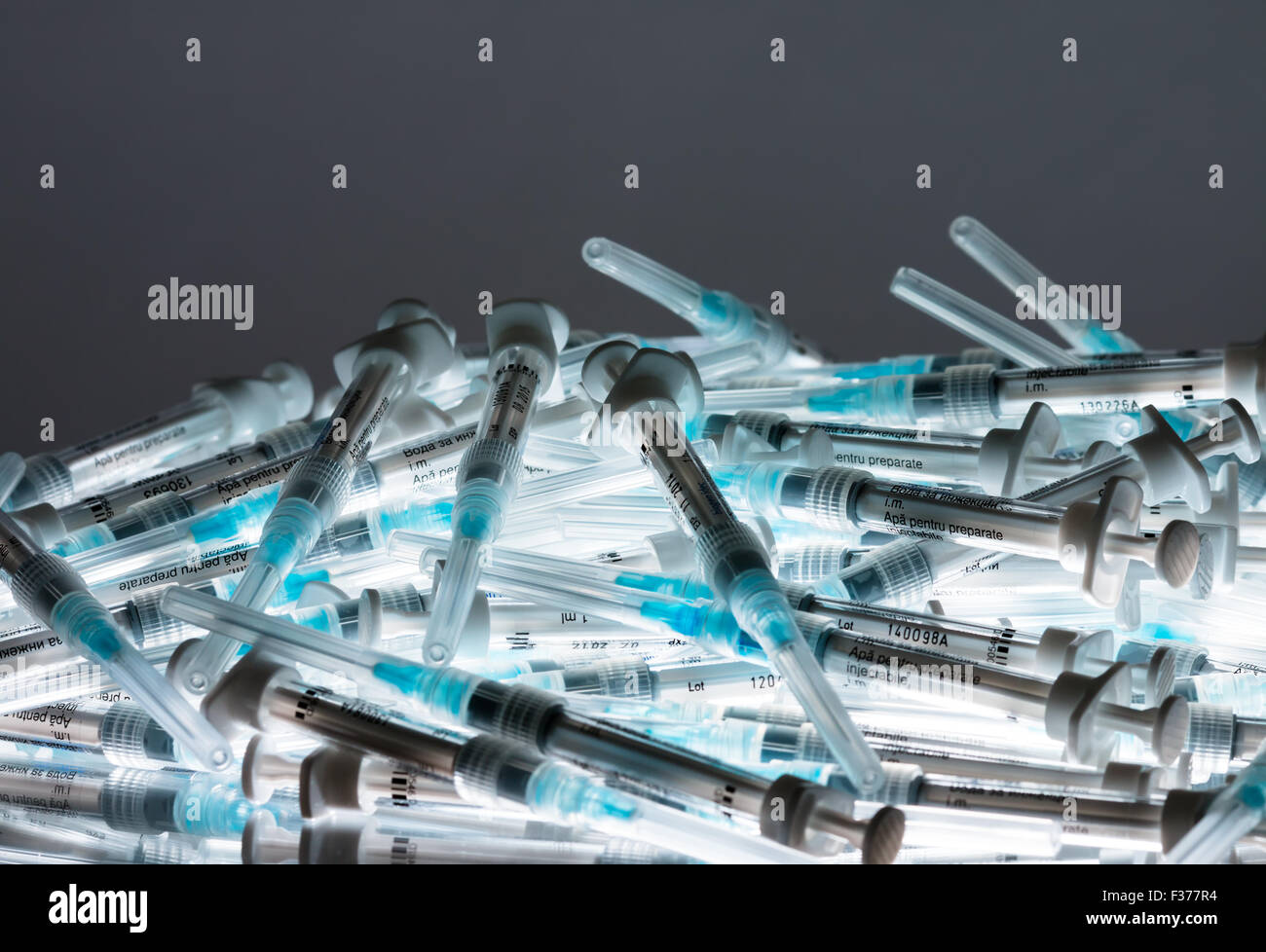 A bunch of used syringes, lit from below. The text on them does not ...