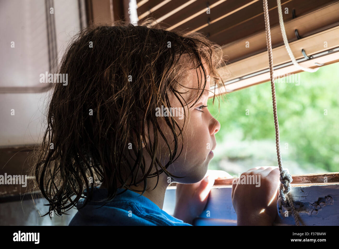 Pensive little girl looking out the window at the sunshine Stock Photo ...