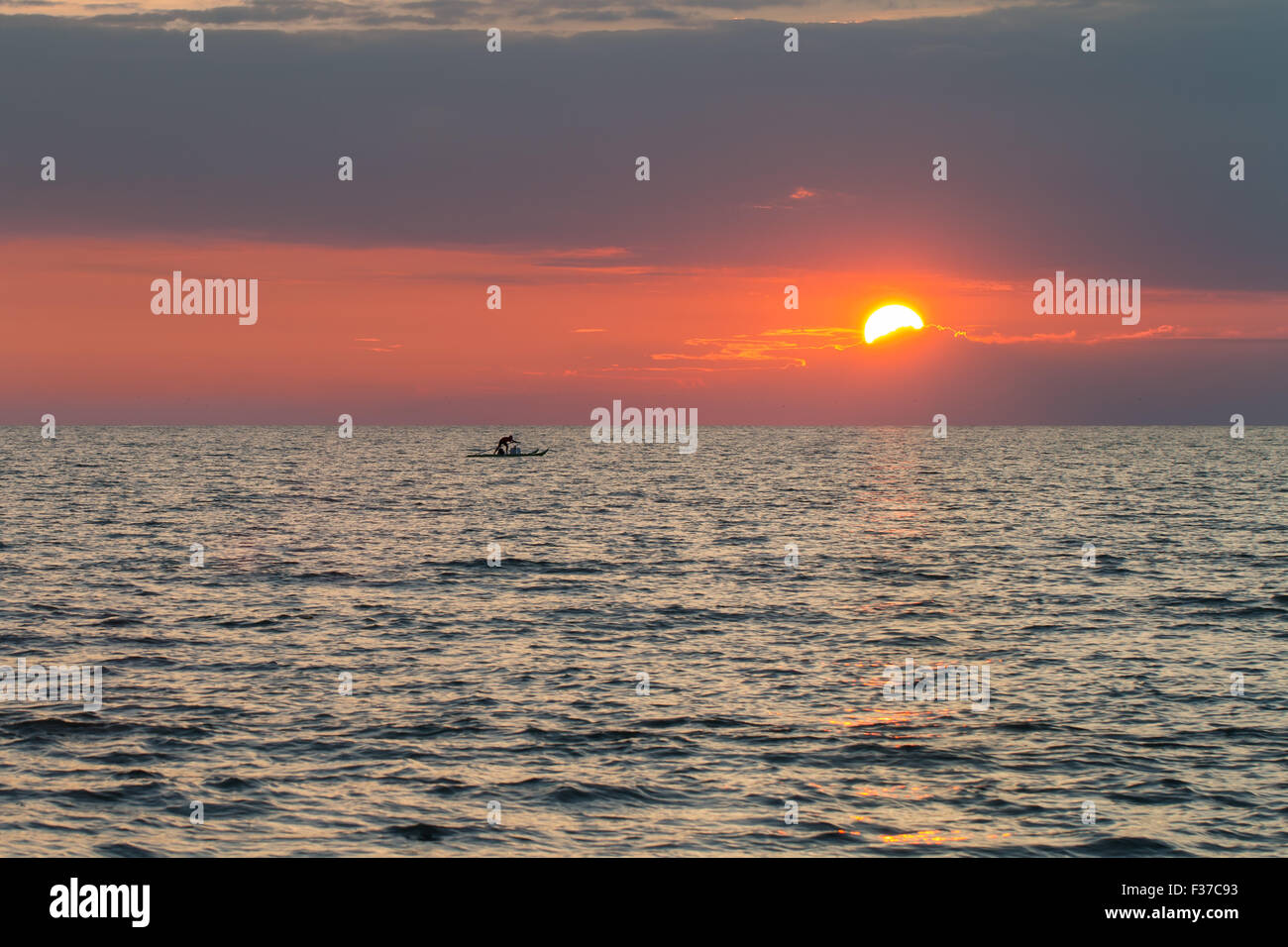Man rowing on a traditional italian boat "pattino" while the sun is ...