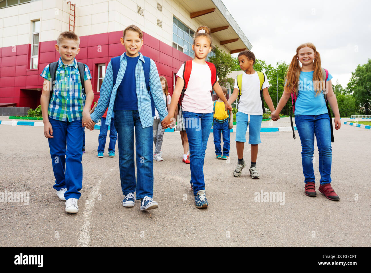 Happy children carry rucksacks, walk near school Stock Photo - Alamy