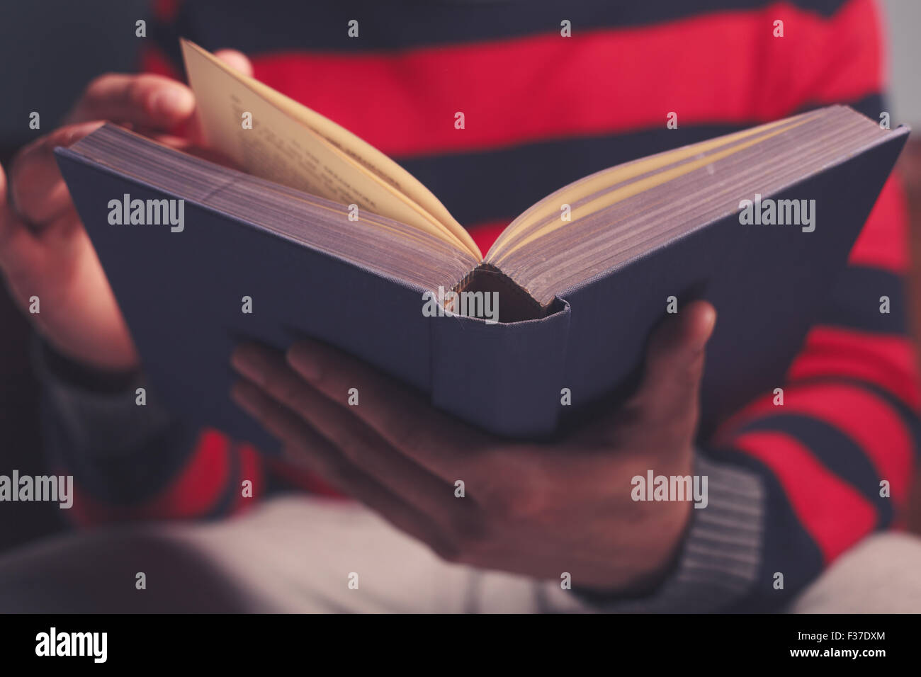 Closeup on a man reading a big heavy book Stock Photo - Alamy