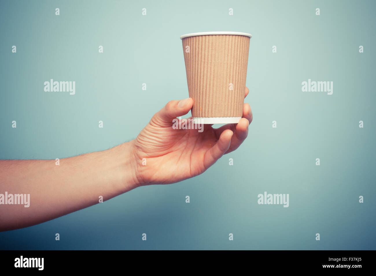 A man is holding a brown paper cup Stock Photo - Alamy