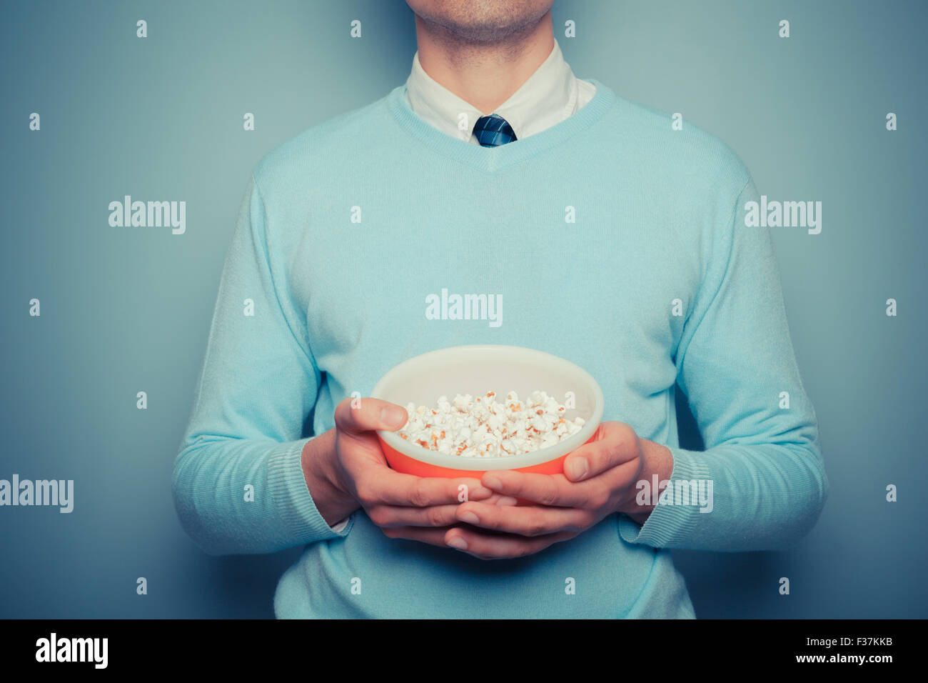 A young man is holding a bowl of popcorn Stock Photo - Alamy