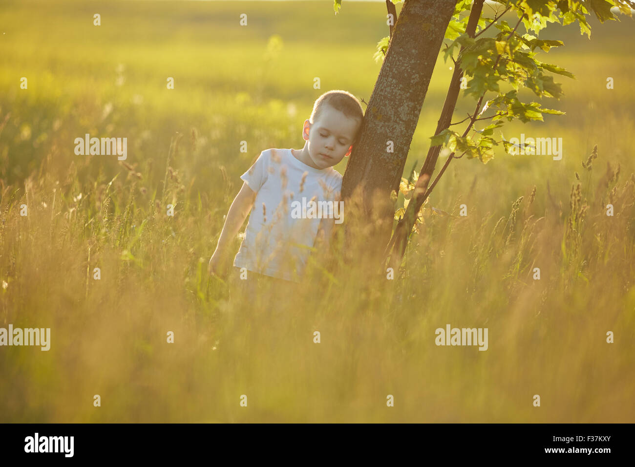 boy is leaning against a tree Stock Photo - Alamy