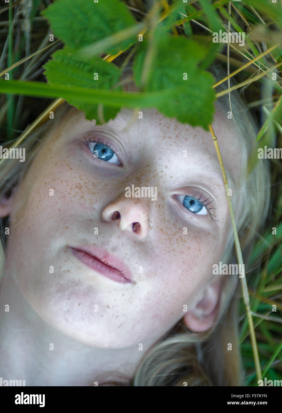 Portrait of a pale faced eight year old girl laying on her back in a ...