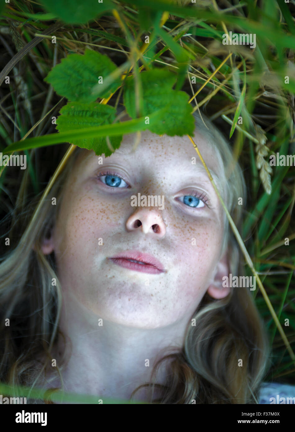 Portrait of a pale faced eight year old girl laying on her back in a ...