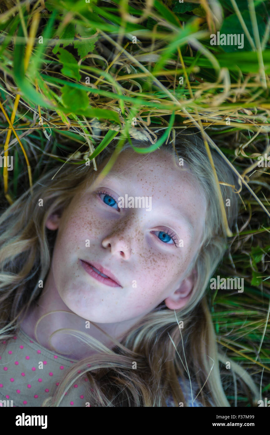 Portrait of a pale faced eight year old girl laying on her back in a ...