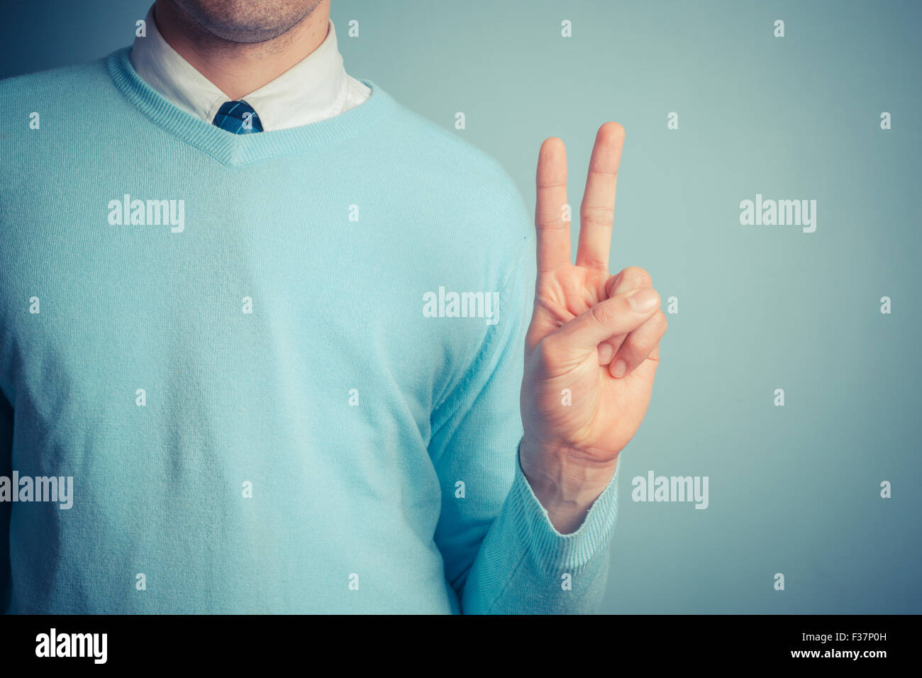 A young man is gesturing a peace sign Stock Photo - Alamy