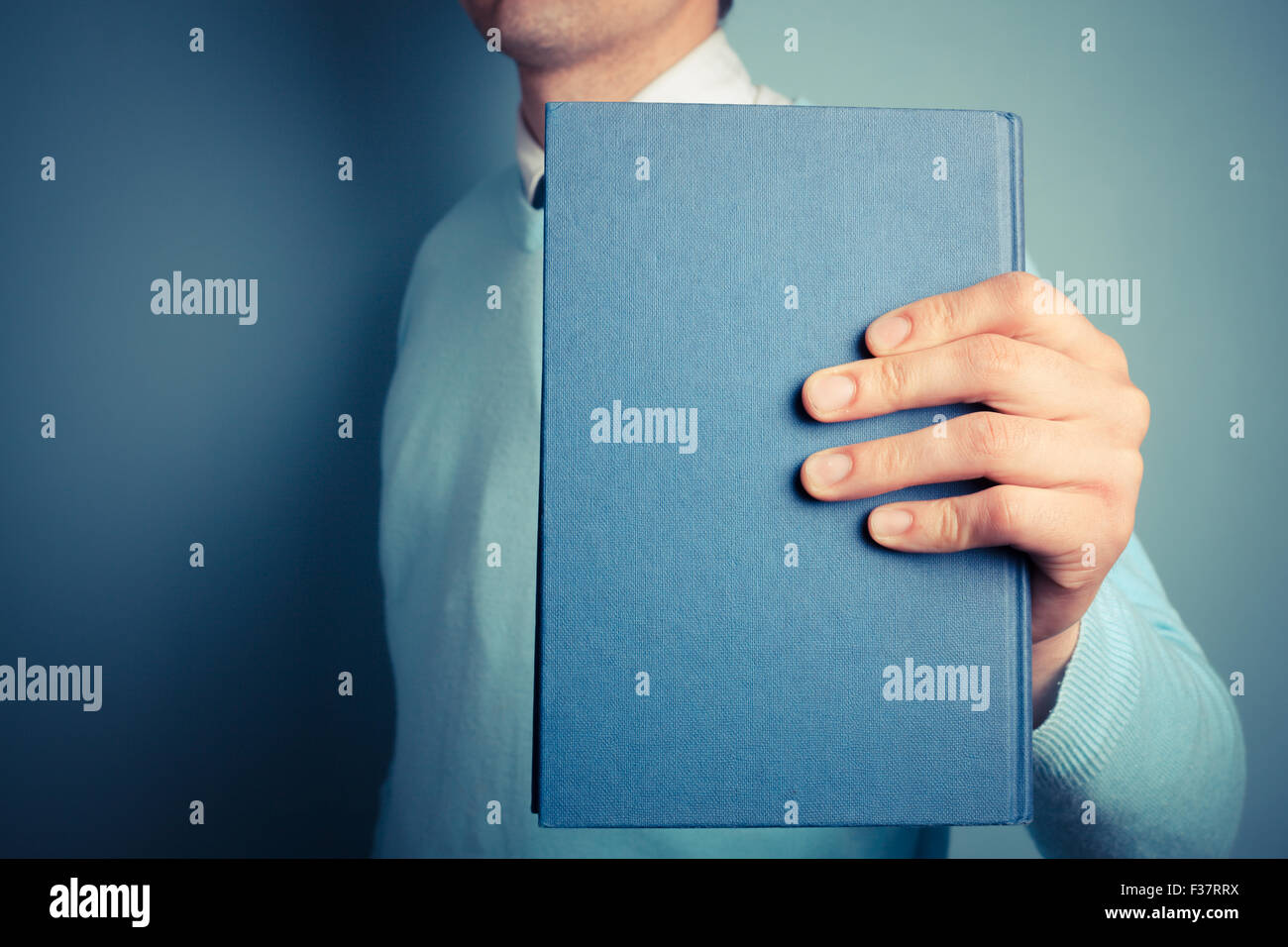 A young man is holding a big blue book Stock Photo - Alamy