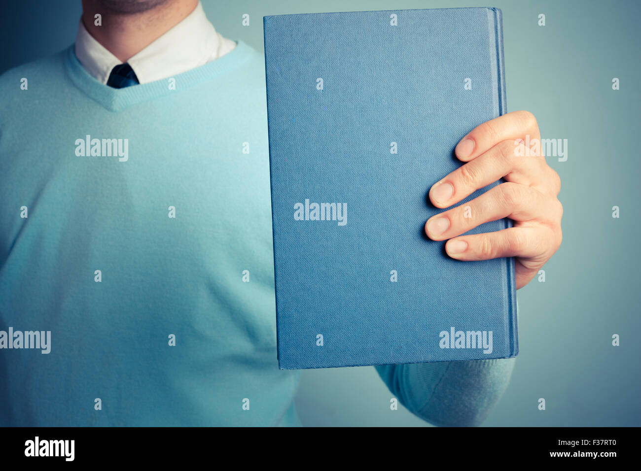 A young man is holding a big blue book Stock Photo - Alamy