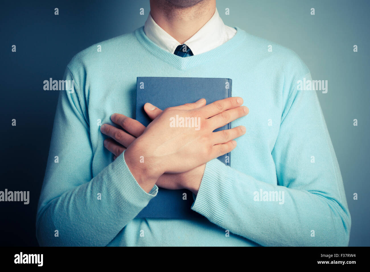 A young man is holding a big blue book Stock Photo - Alamy