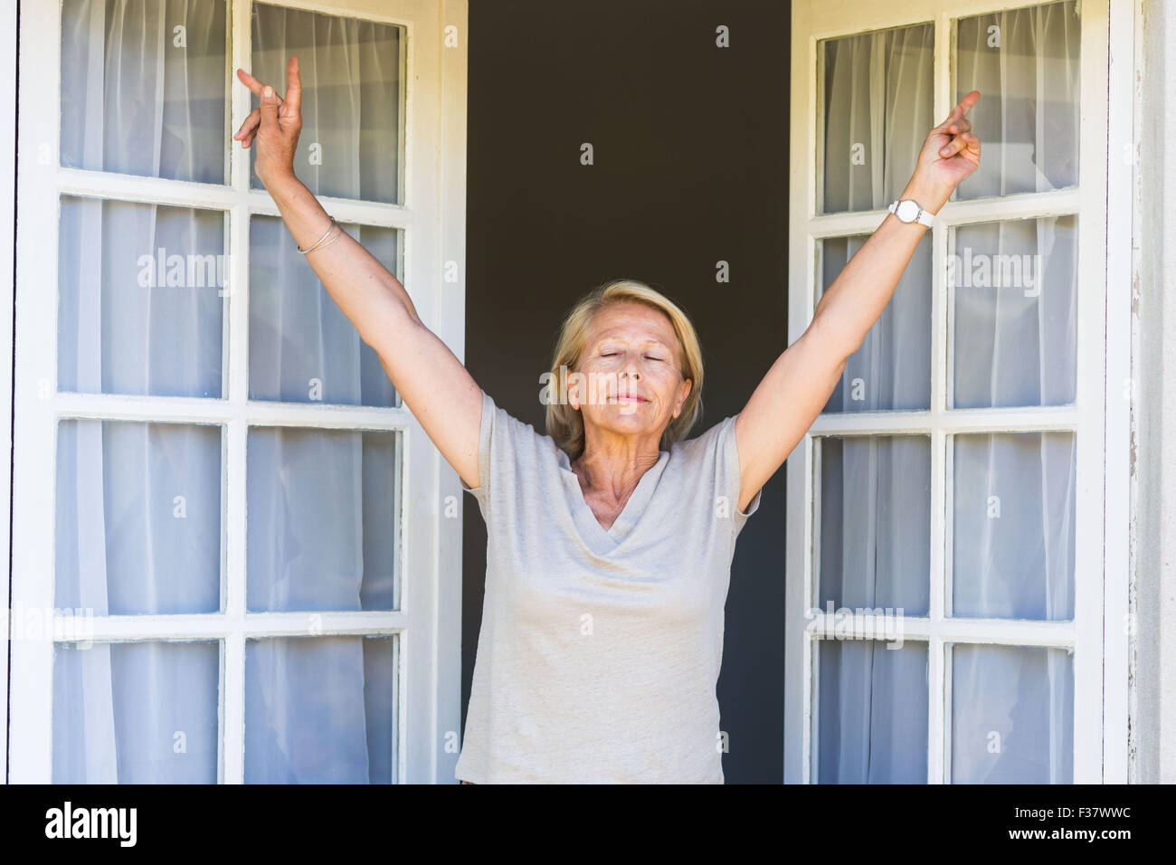 Woman stretching arms by the window Stock Photo - Alamy