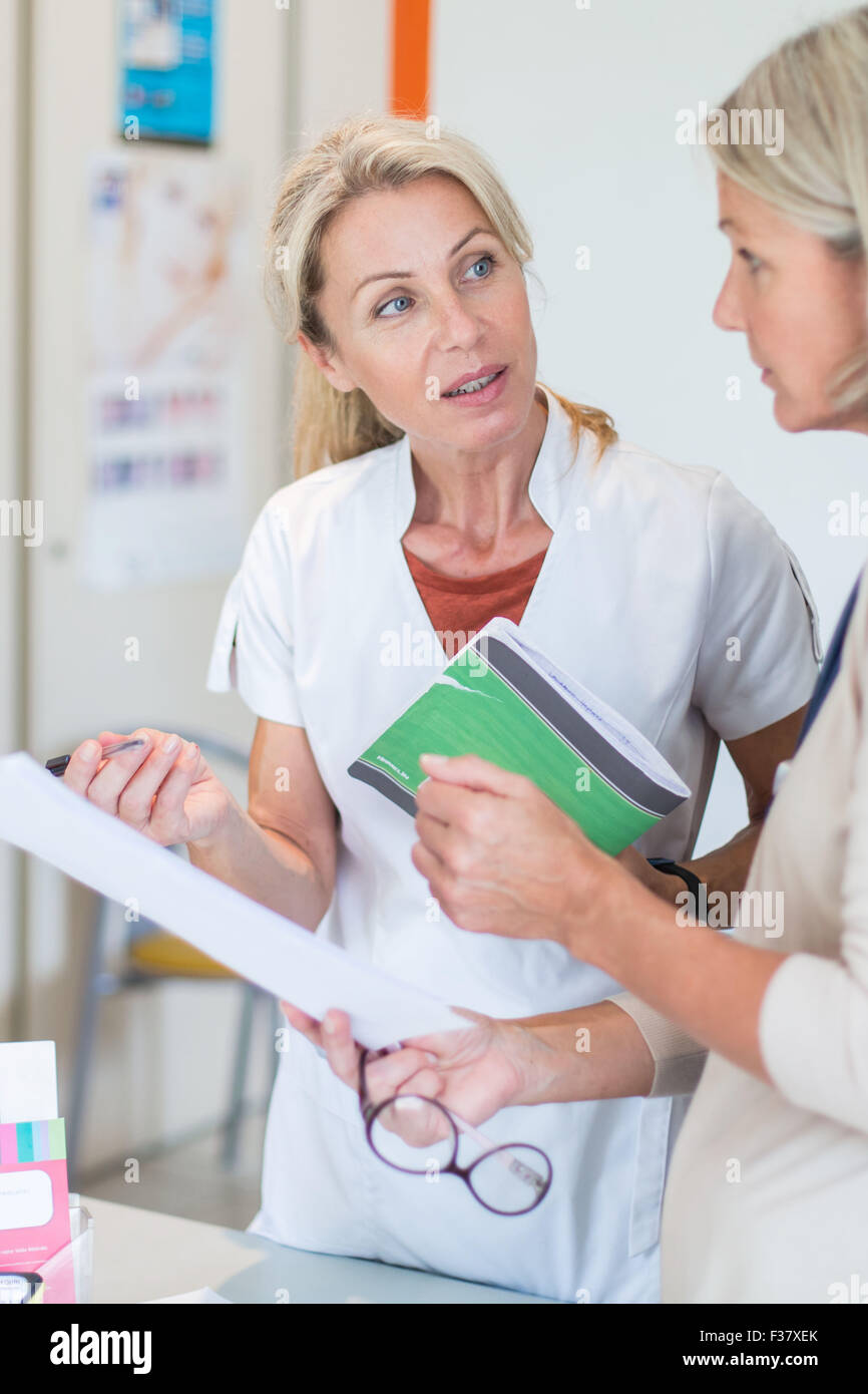 A medical secretary receives instructions from the doctor she assists ...