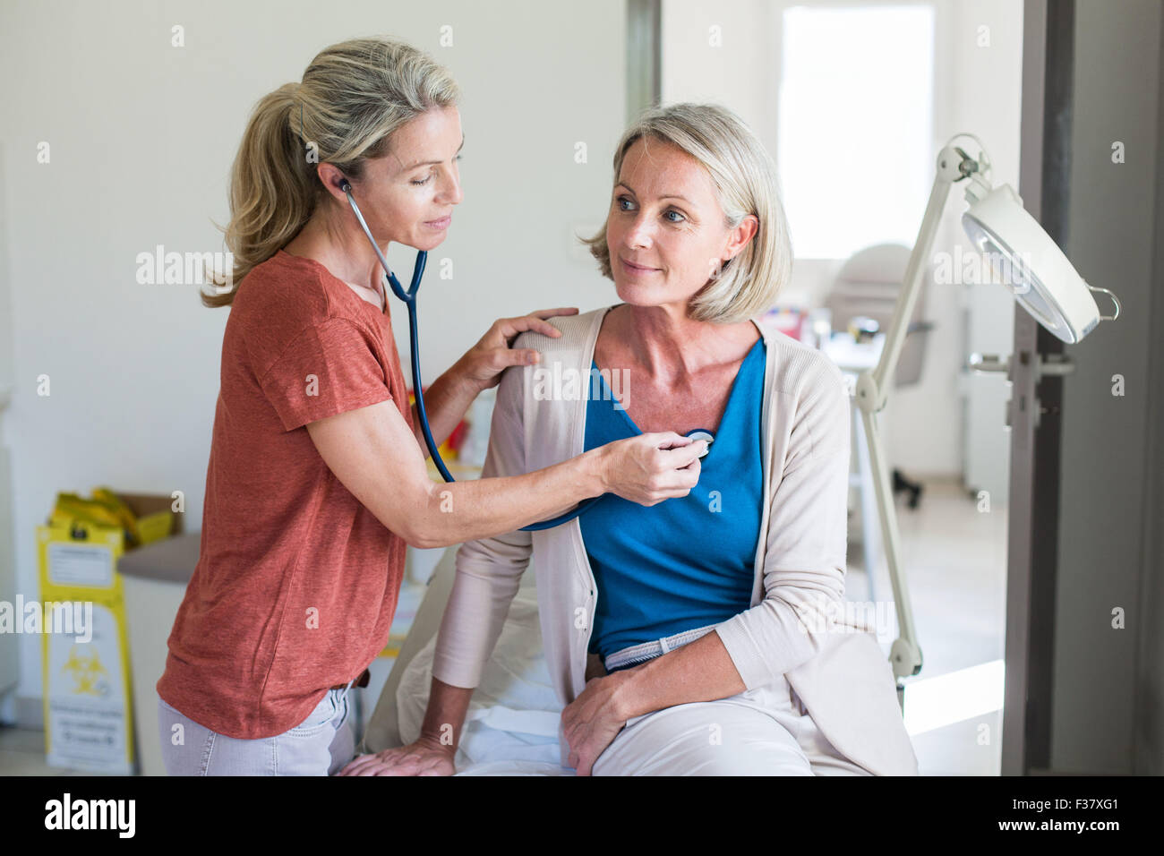 Doctor examining a female patient with a stethoscope Stock Photo - Alamy