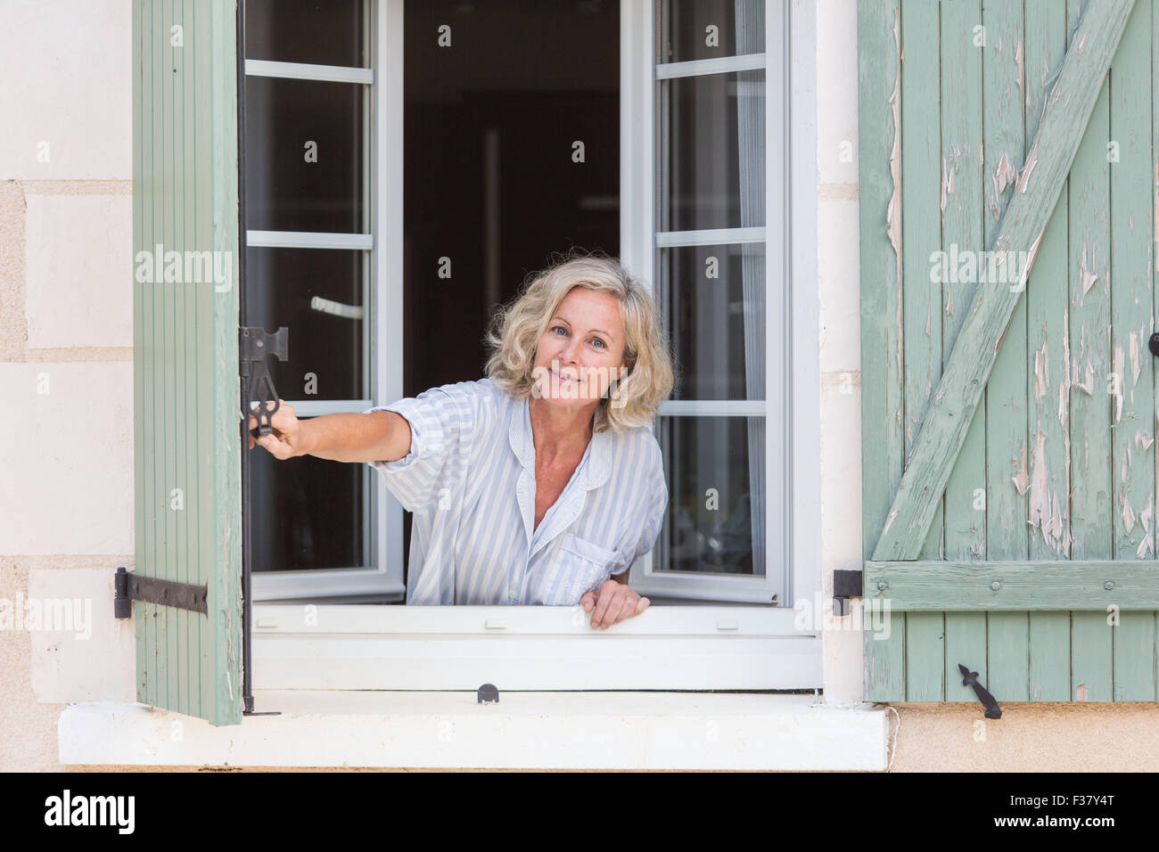 Woman opening shutters Stock Photo - Alamy