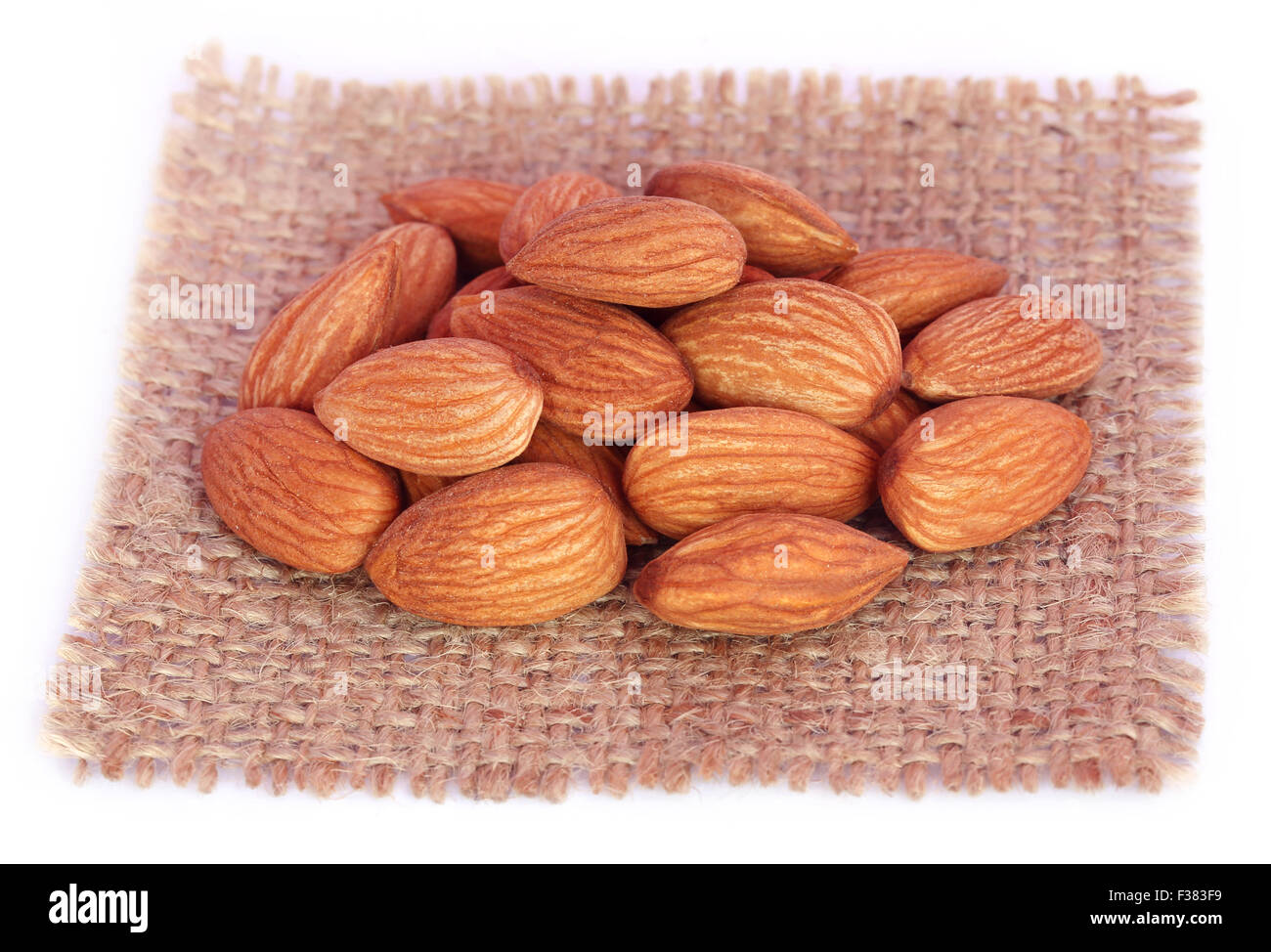Fresh almonds on sack over white background Stock Photo - Alamy