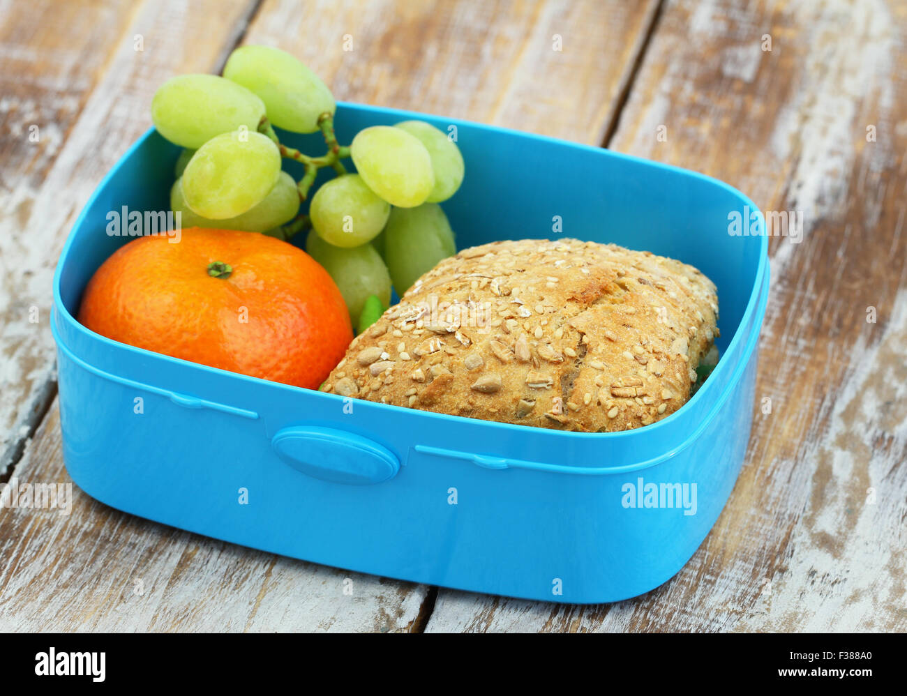 School lunch box with whole grain bread roll, grapes and mandarine on ...