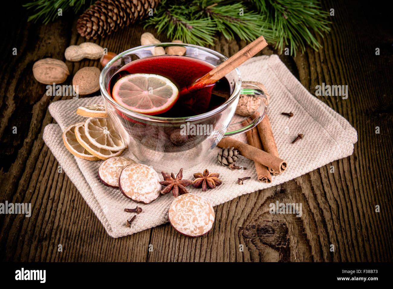 Mulled wine in glass with cinnamon stick, gingerbread and nuts, close ...