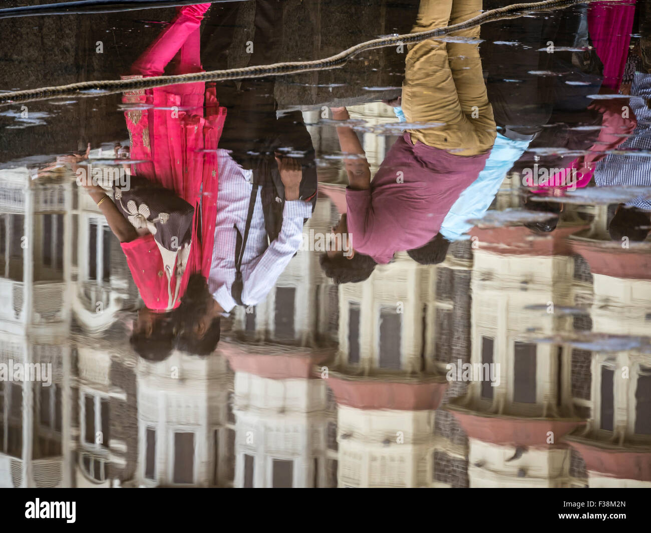 Reflections of the Taj Mahal hotel in a water puddle, people looking ...