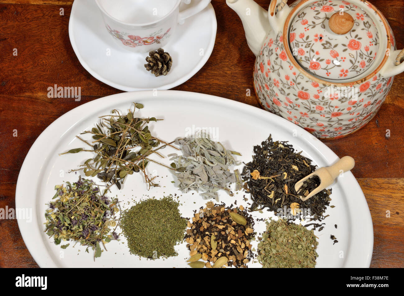 Piles of different sorts of tea on white plate, porcelain tea cup and ...