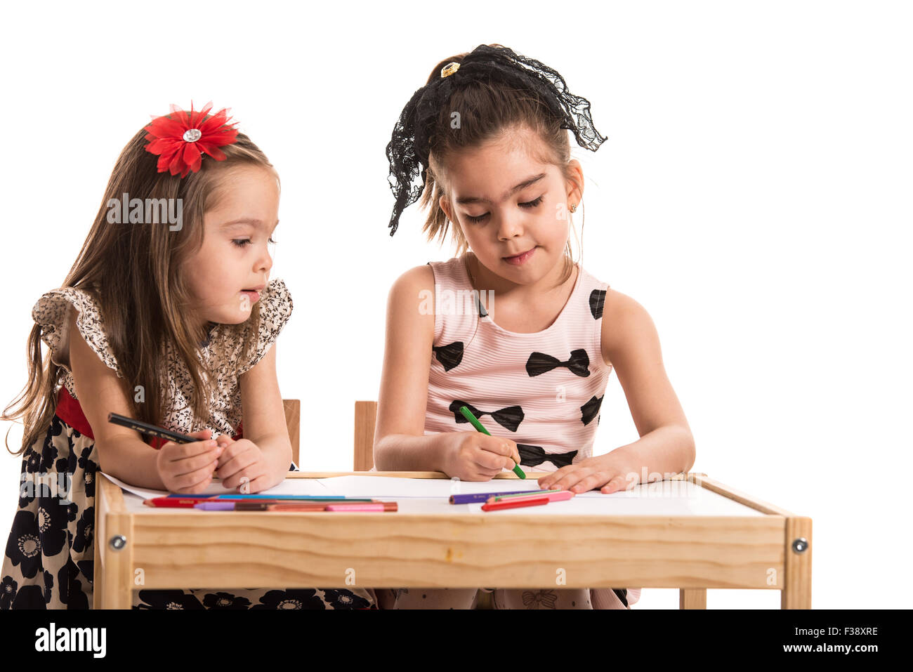 Two little girls sitting at table and dawing isolated on white ...