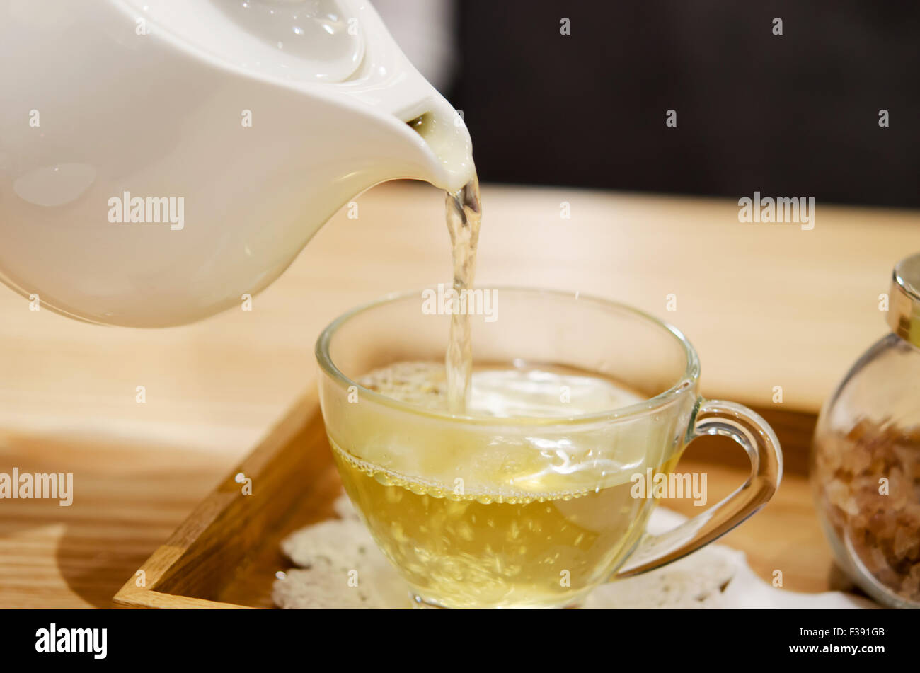 Teapot pouring tea into a cup on a table Stock Photo - Alamy