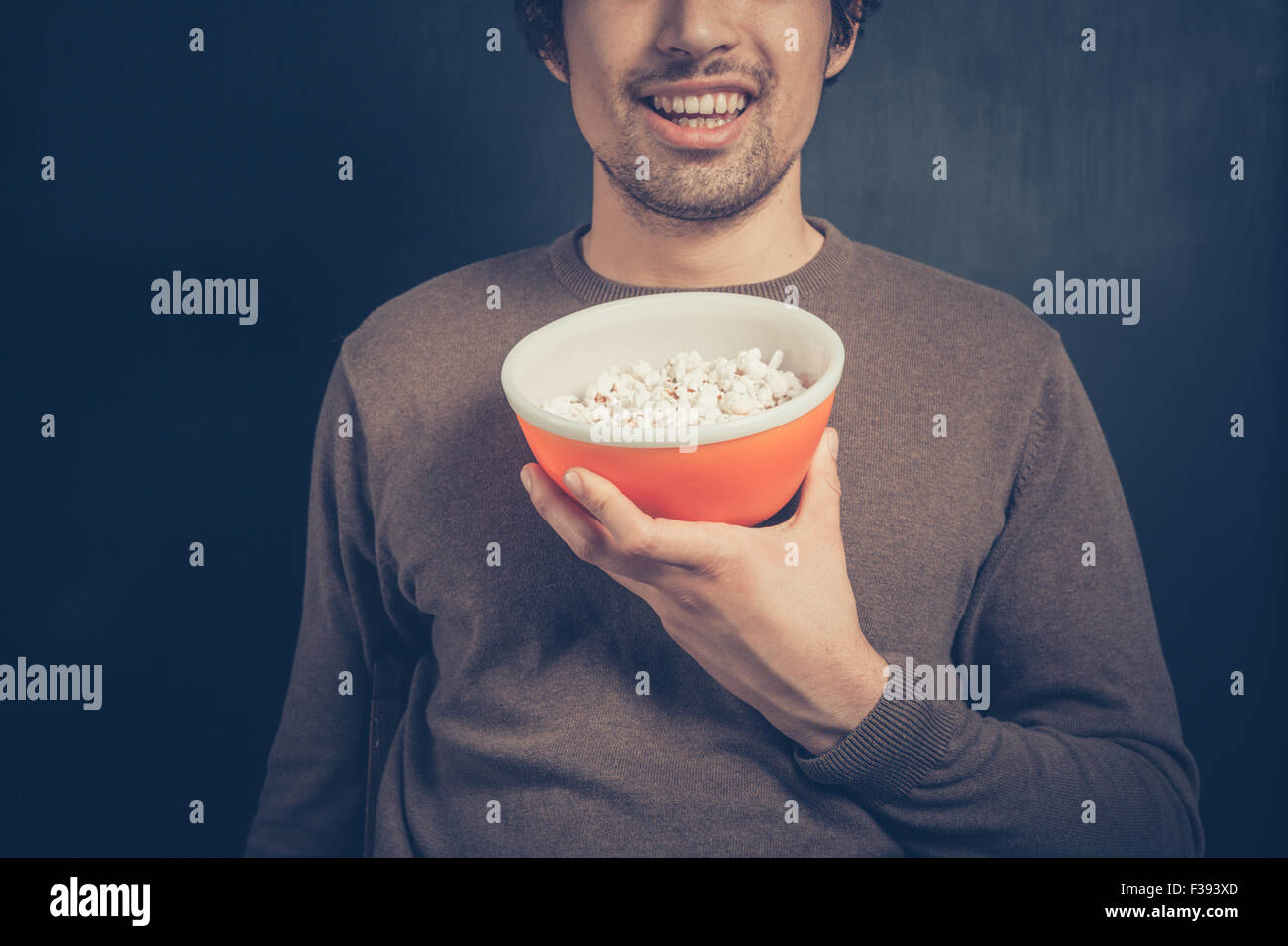 A smiling young man is holding a bowl of popcorn Stock Photo - Alamy